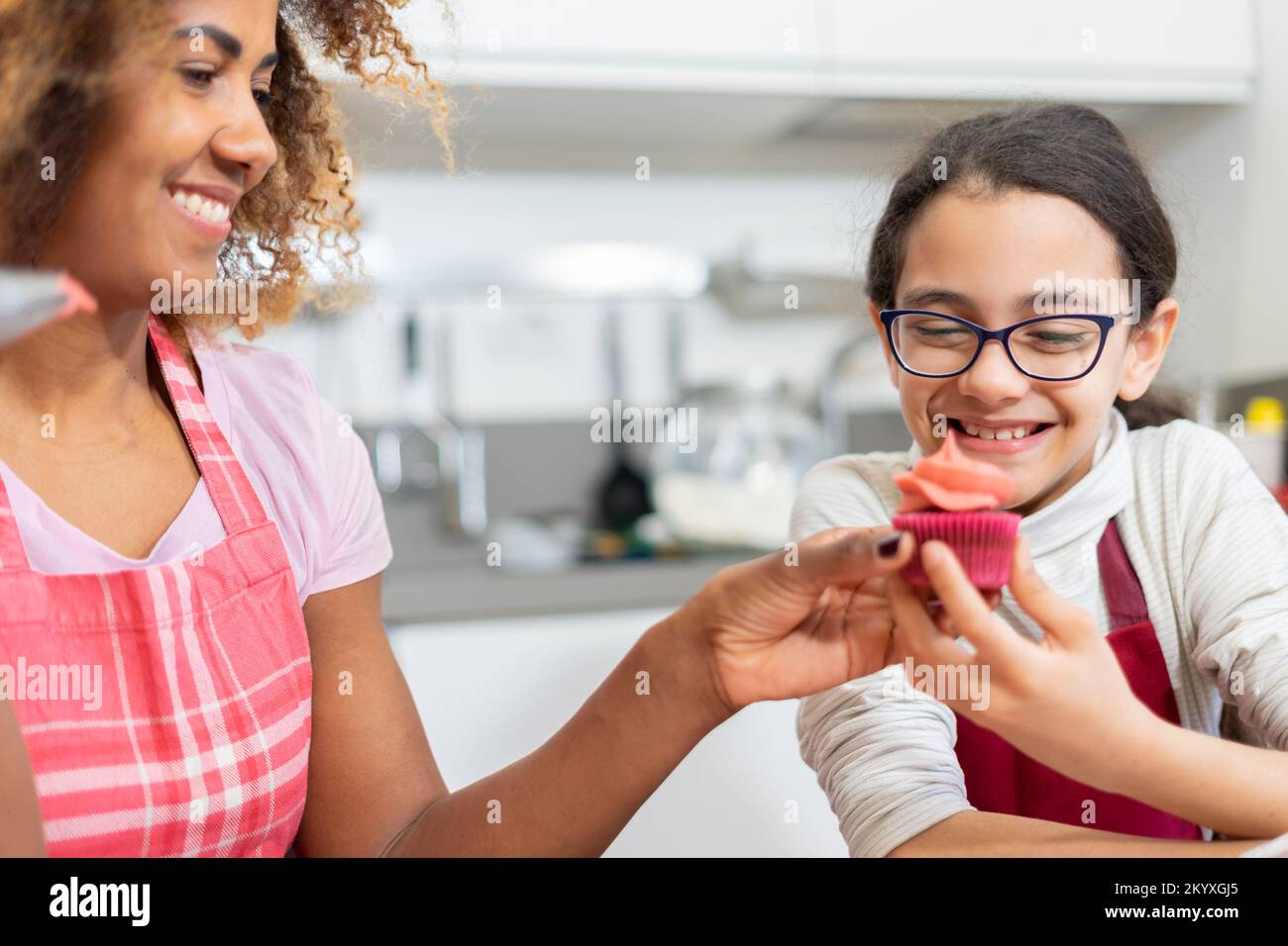Brazilian woman showing to his daughter how to decorating a cup cake ...