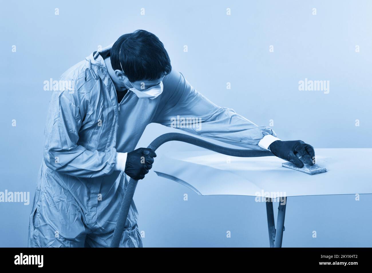 Auto mechanic wearing face mask buffing and polishing car hood in auto ...