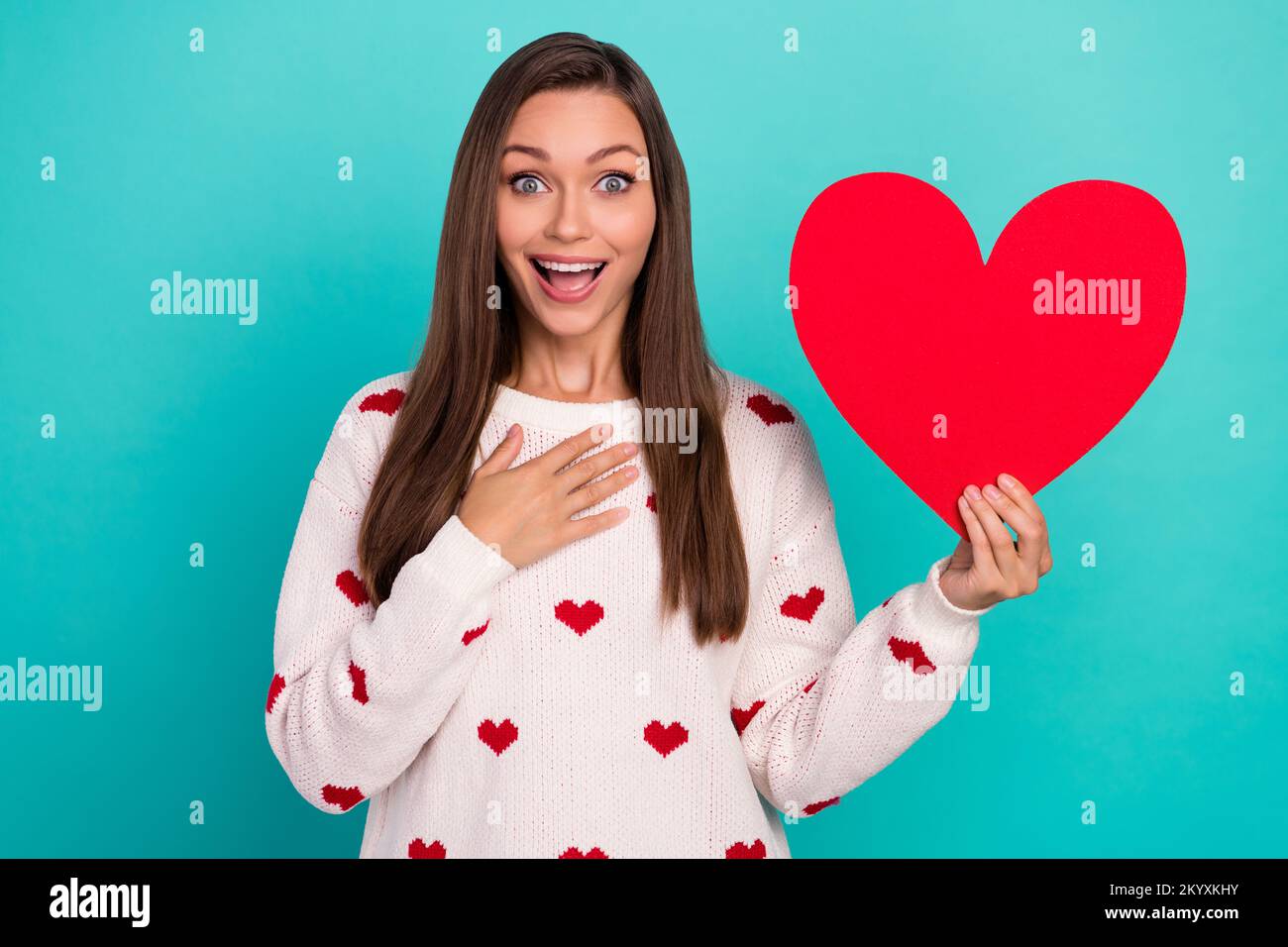 Photo of astonished positive girl hold large red paper heart hand touch ...