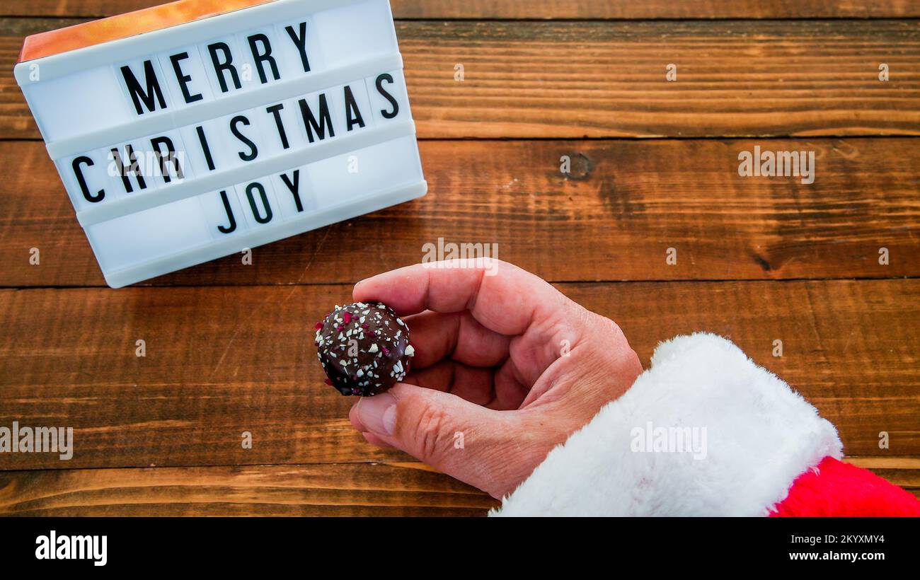 Santa Claus is holding chocolate candy in his hand with wish text in ...
