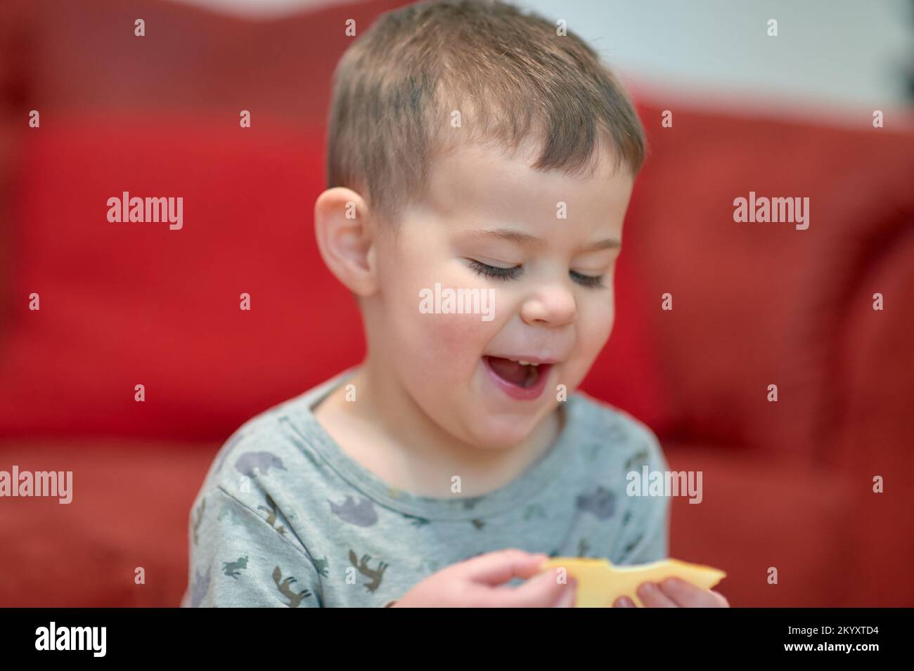 cute young boy eating cheese at home while watching tv next to the ...