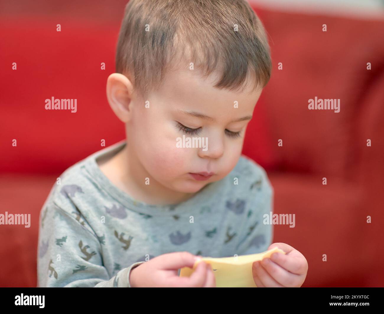 cute young boy eating cheese at home while watching tv next to the ...