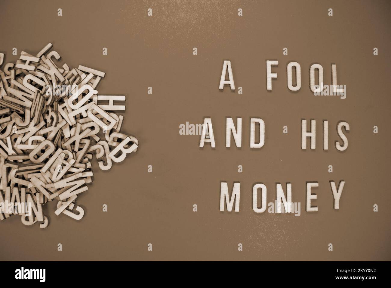 A FOOL AND HIS MONEY in wooden English language capital letters ...