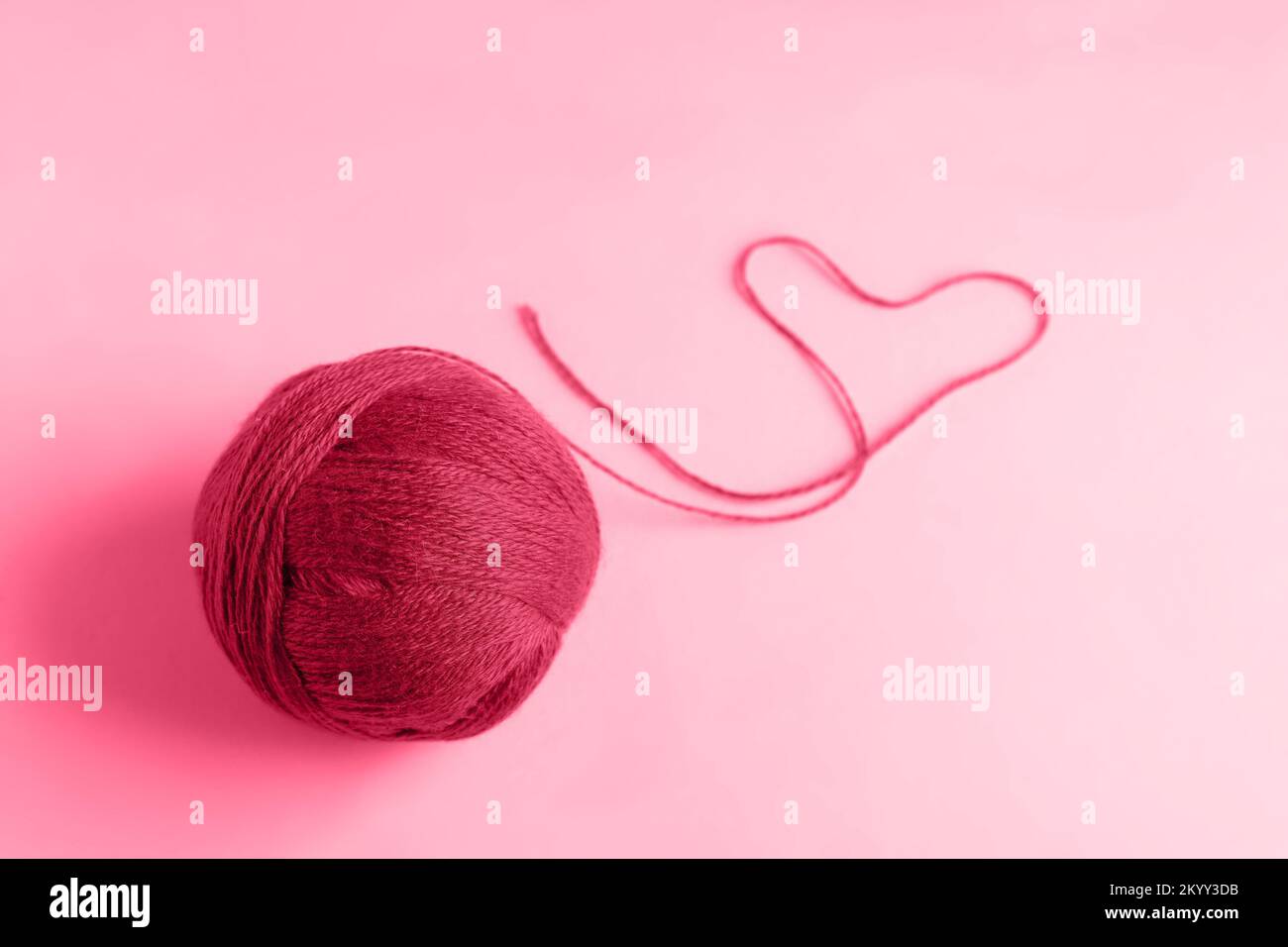 Magenta ball of thread with a heart of thread on the table ...