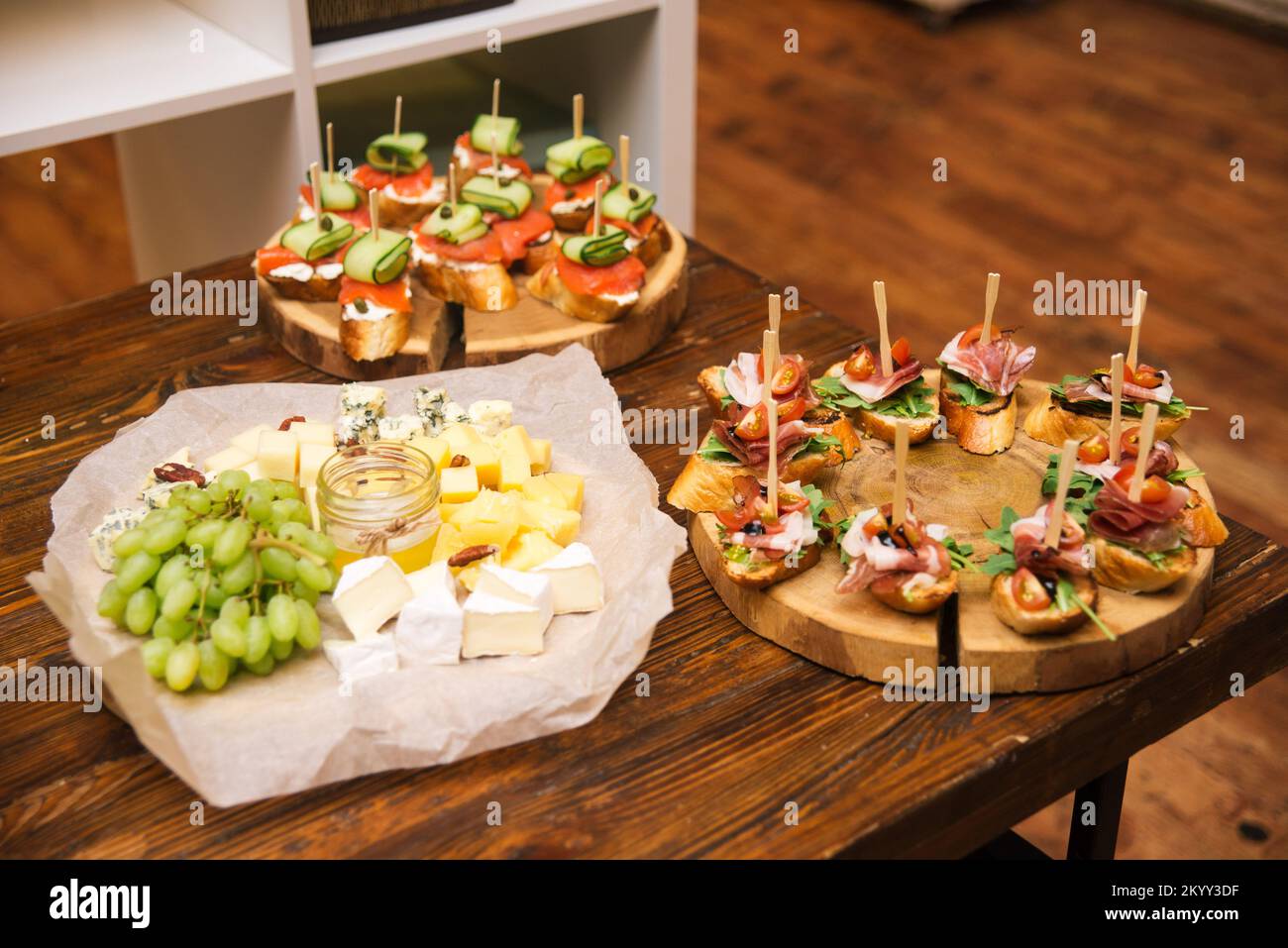 a table of cold party appetizers. a set of cheese slices with grapes ...