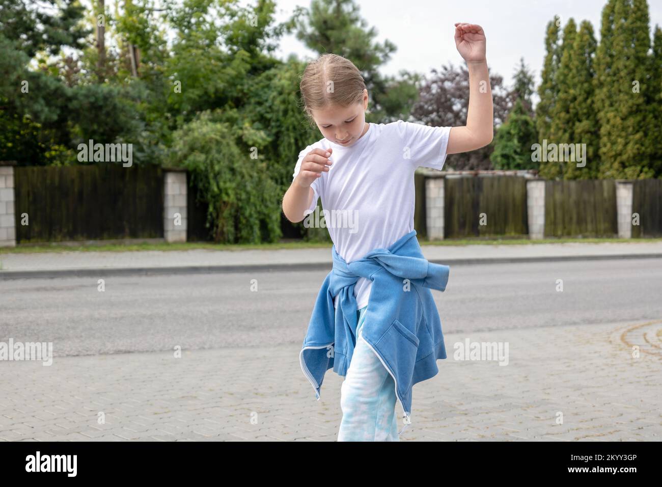 Happy elementary school age girl, child dancing through the street ...