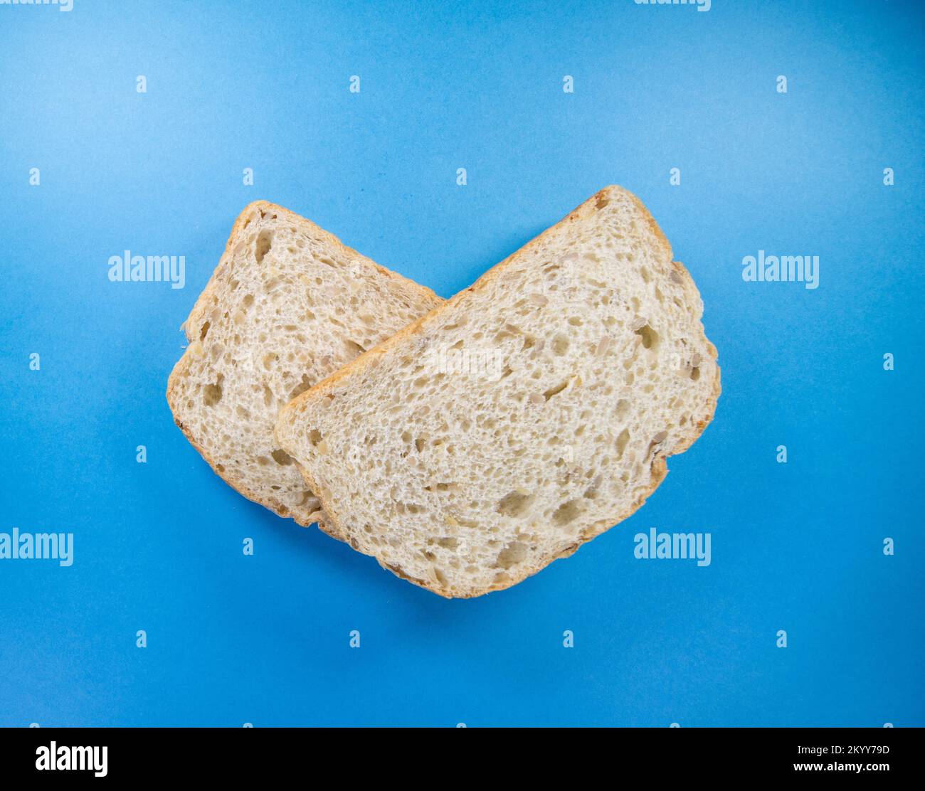 two slices of fresh seeded bread isolated on a dark blue background ...