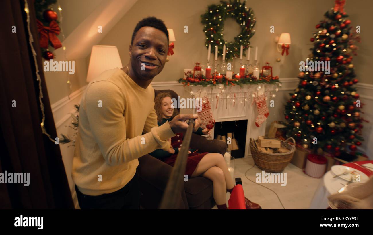 African American man with selfie stick records video, shows table with ...