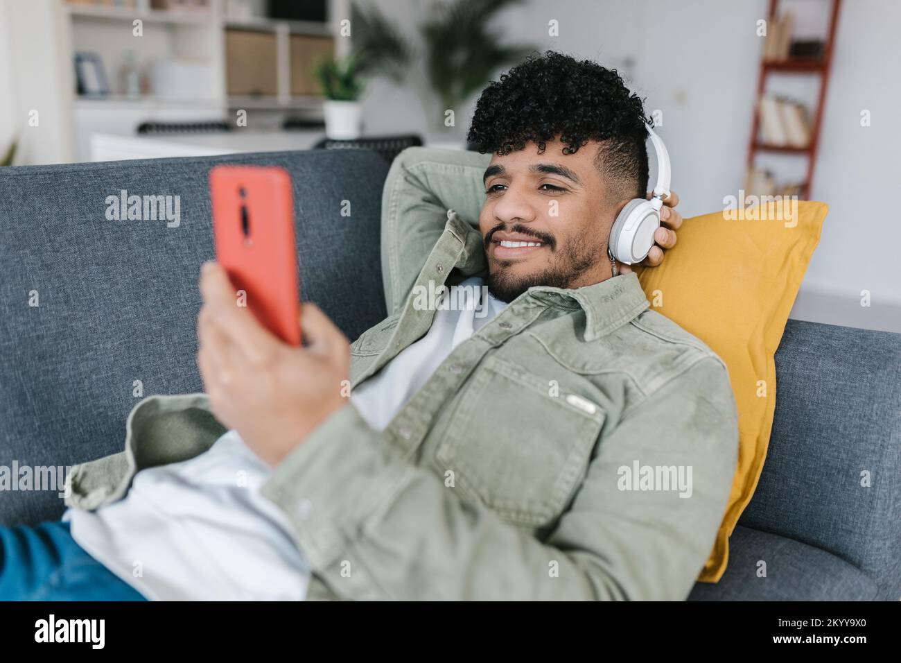 Latin american young man relaxing on sofa watching social media on ...