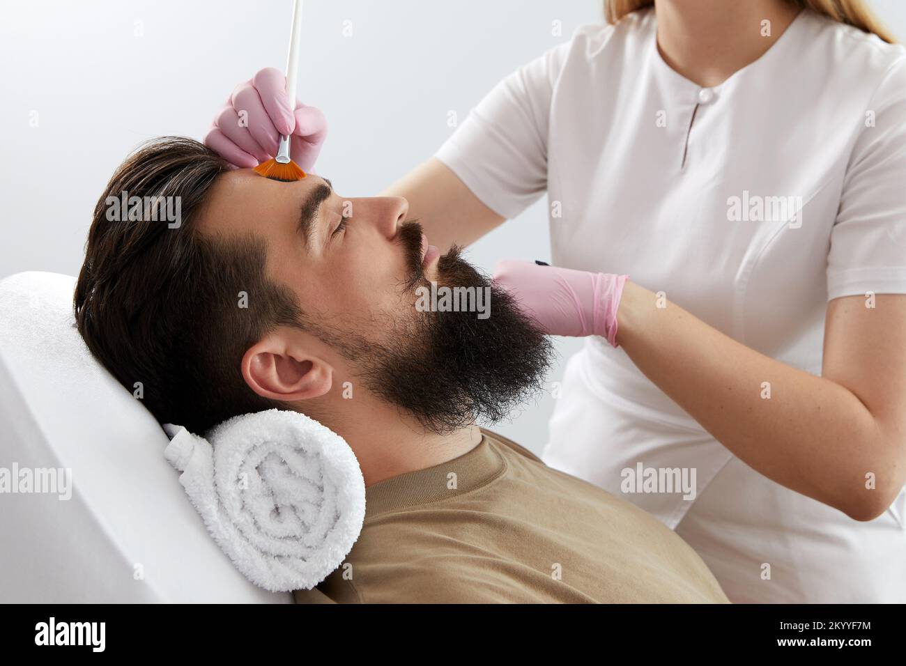 Cosmetologist applying a clay mask to male face with brush. Spa ...