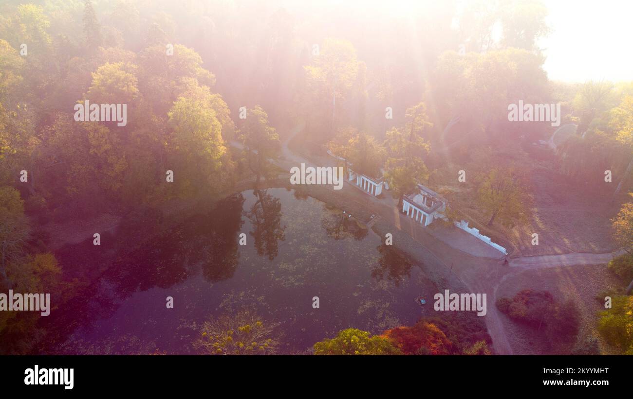 Aerial drone view over lake with swans, architectural columns and trees ...