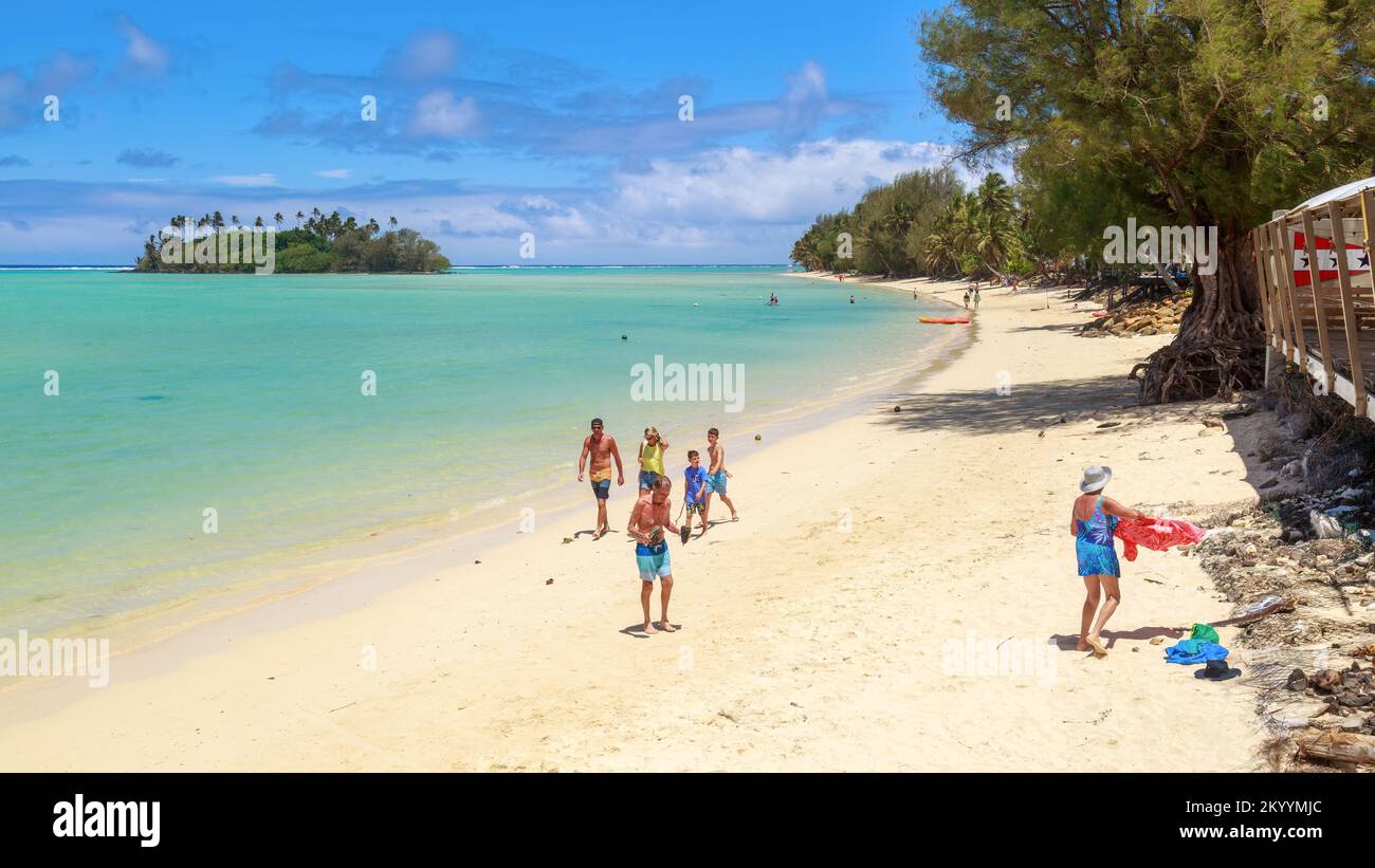 Tourists walking on beautiful Muri Beach on the tropical island of ...