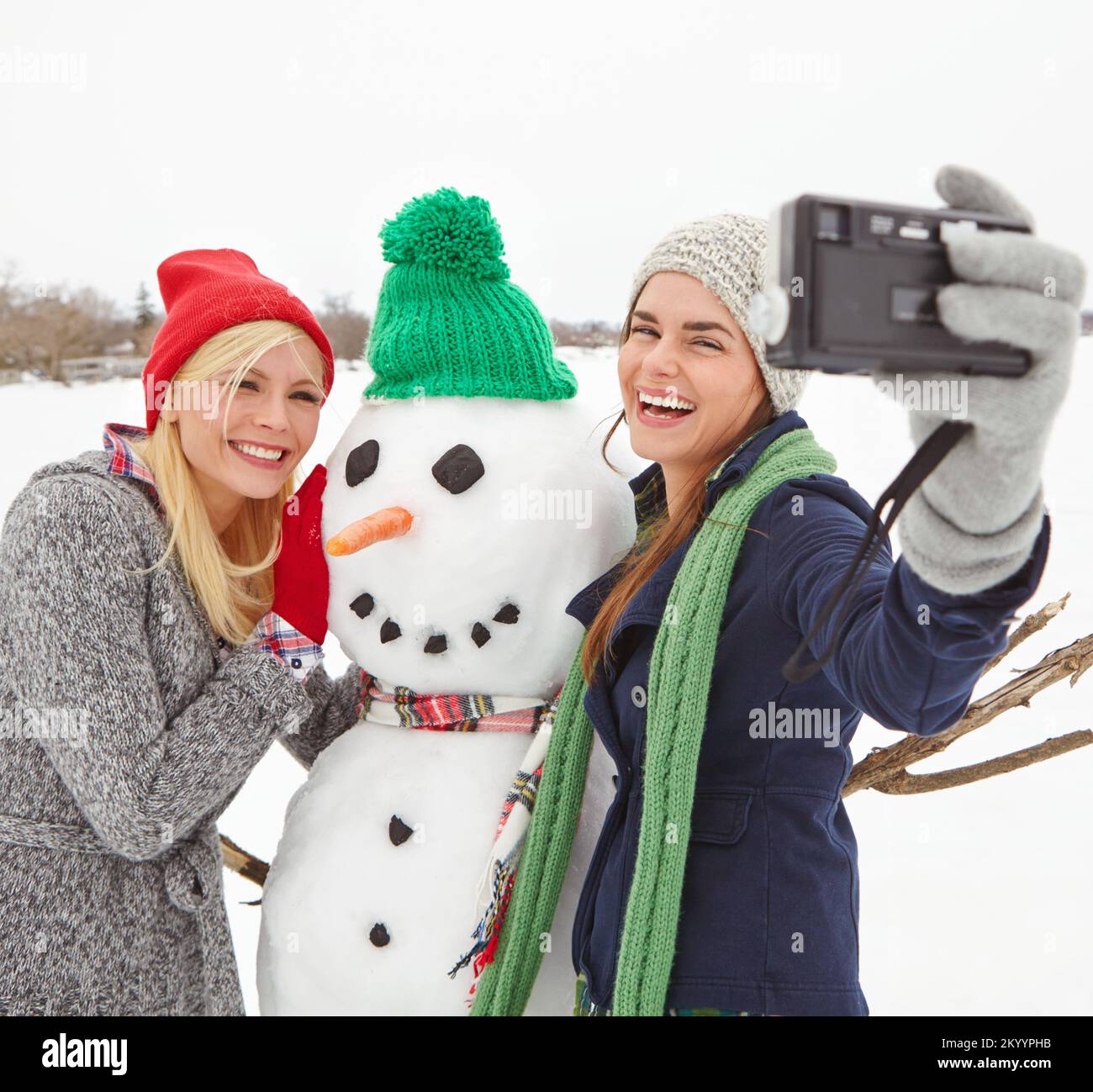 Selfie, snowman and winter with woman friends taking a photograph ...