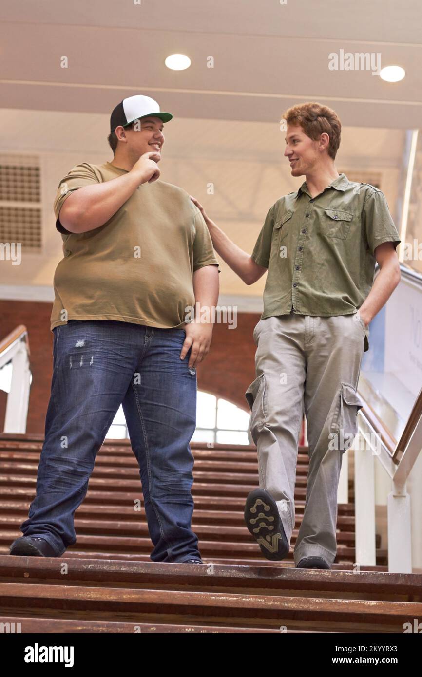 On their way out. Two young men walking down a flight of stair together ...