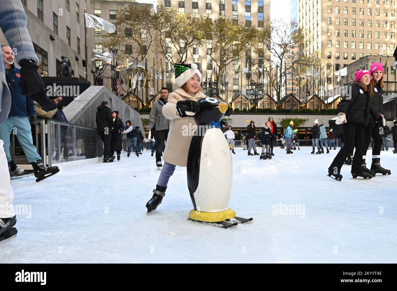 A young skater holds on to a penguin skating aid as she learns to ...