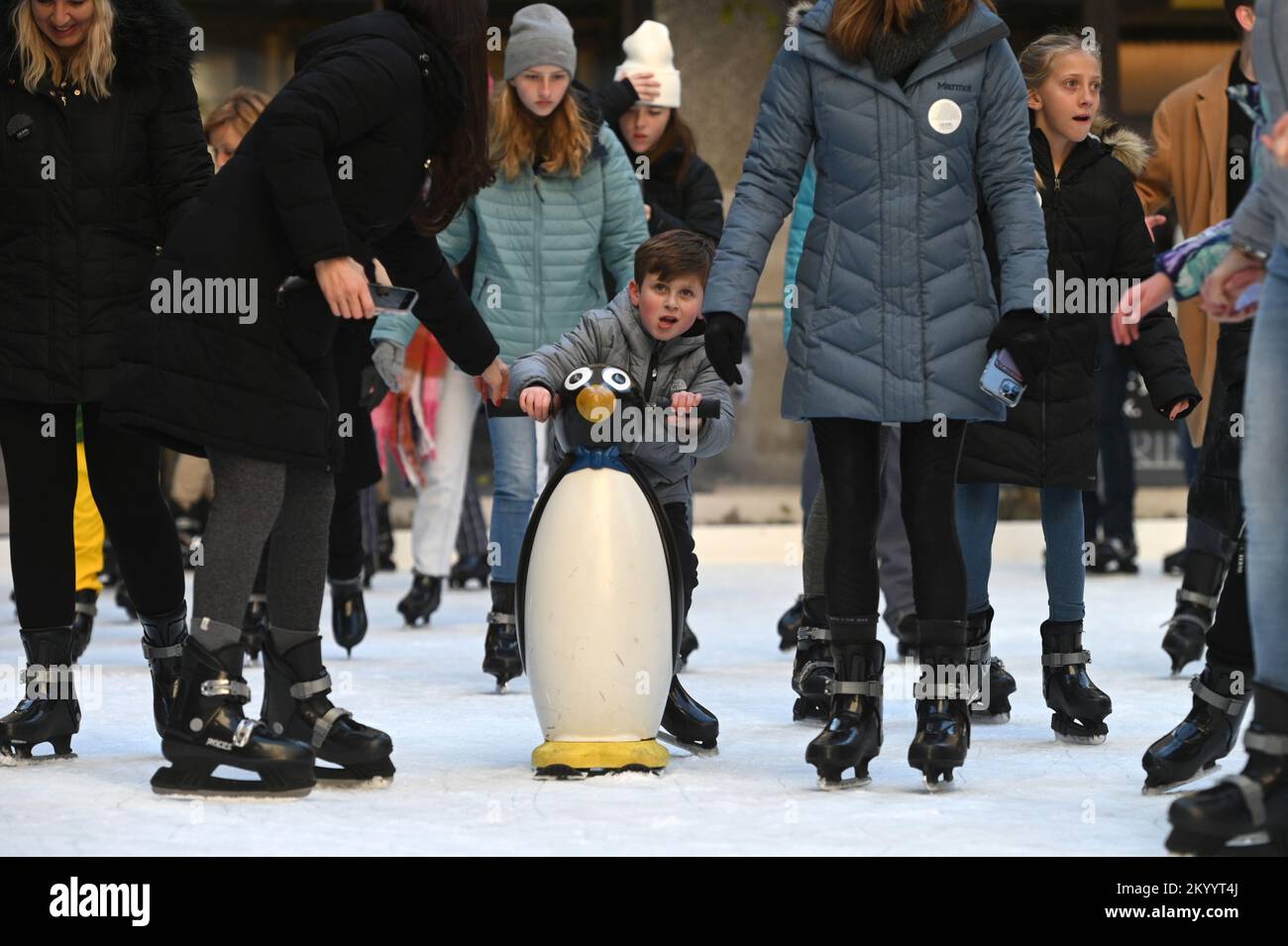 A young skater holds on to a penguin skating aid as he learns to ...