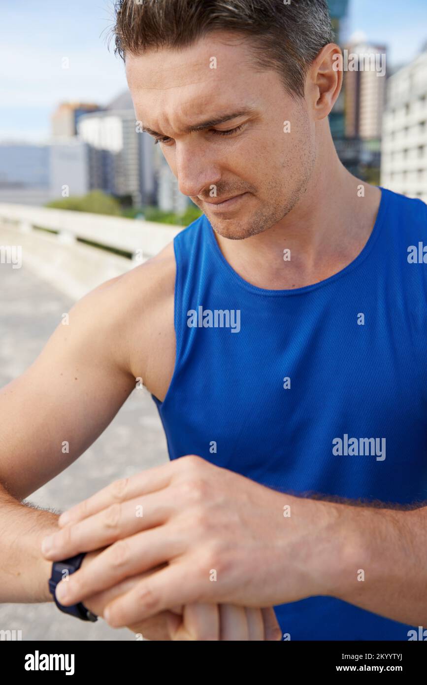 Time trial day. Cropped image of a male runner setting his watch before ...