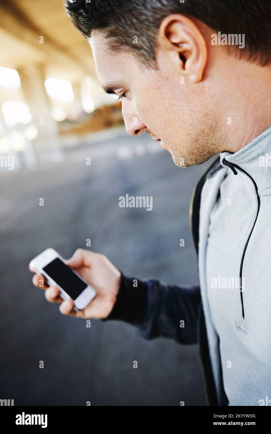 Texting on the go. Side view of a young man checking something on his ...