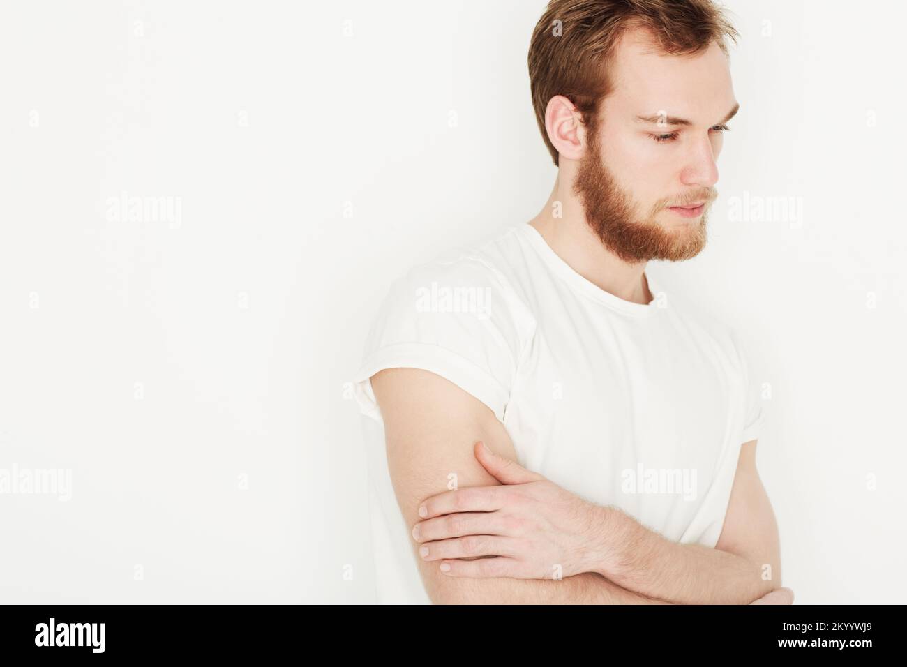Feeling down...A young man standing with his arms folded while wearing ...