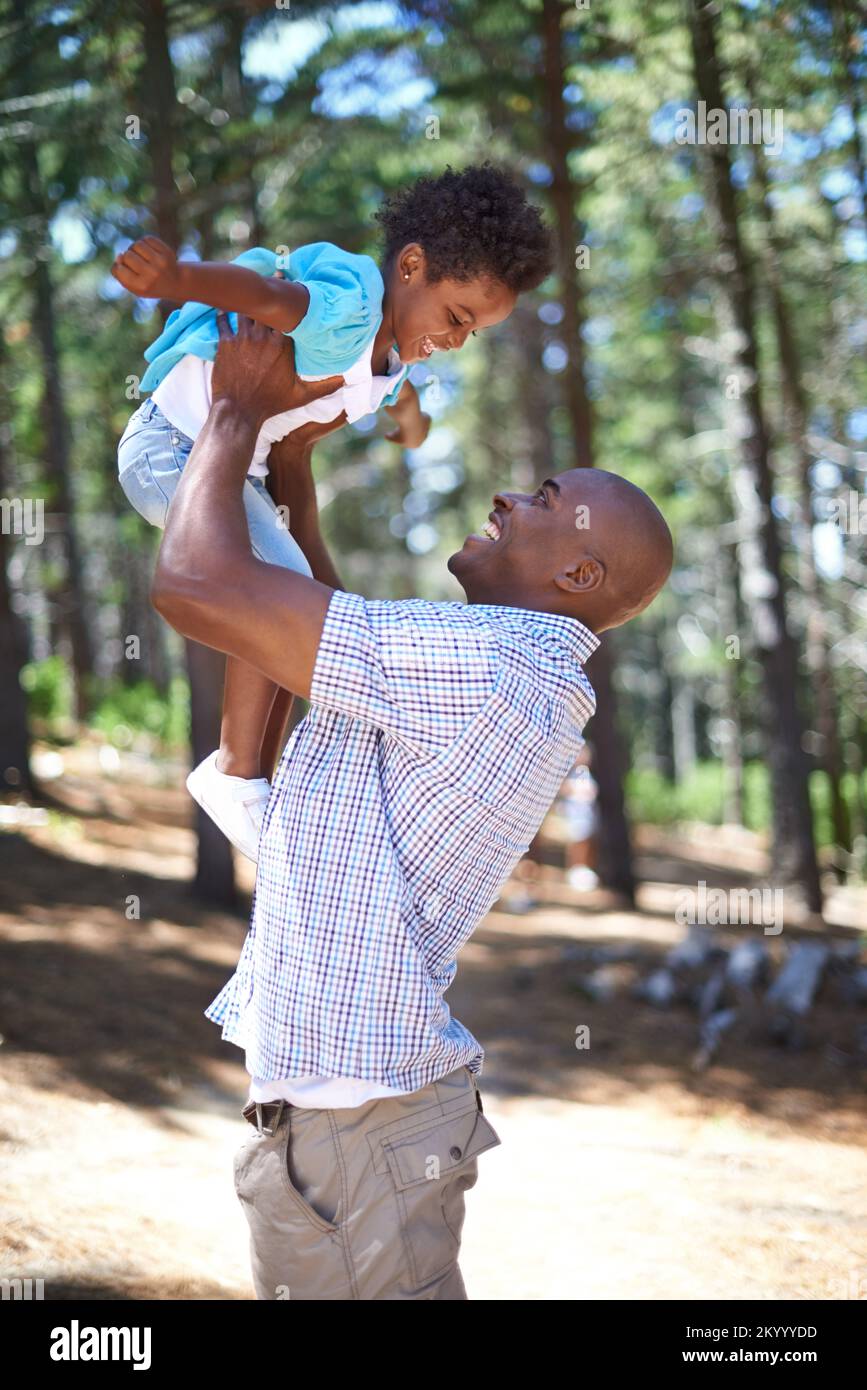Higher dad, higher. A happy young african father playing with his ...