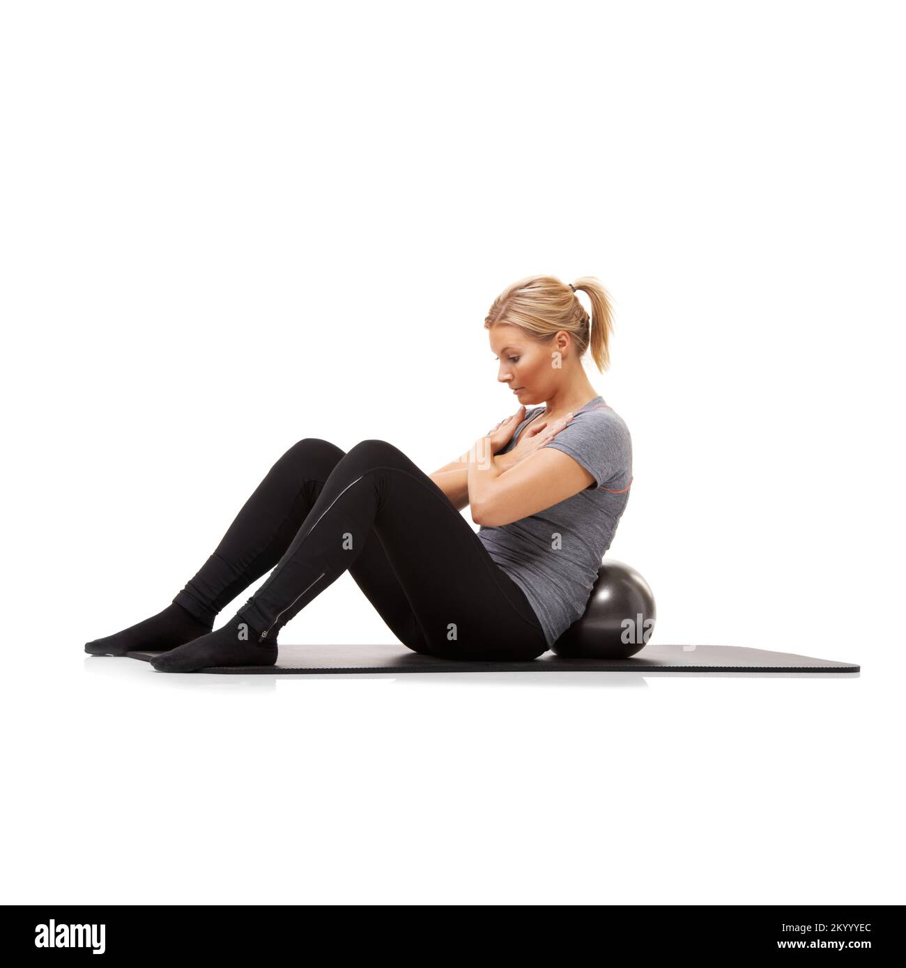 Just a few more reps. A young woman doing sit-ups on an exercise ball ...