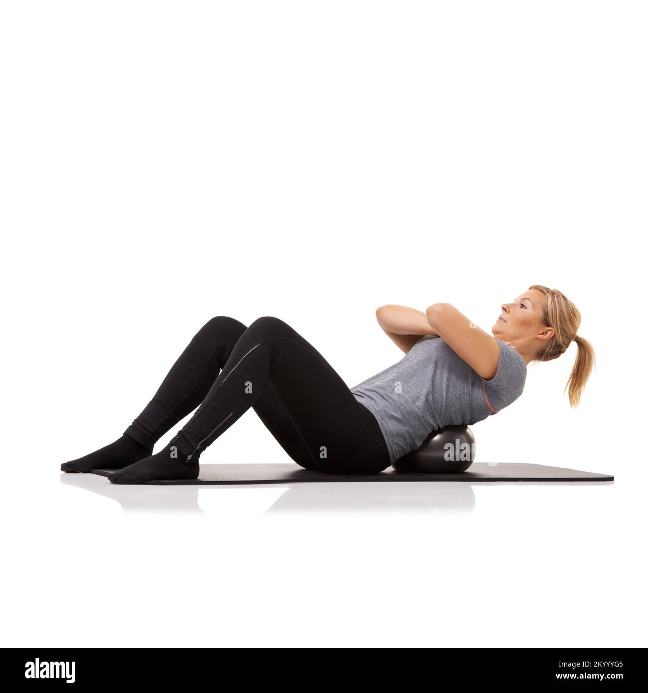 Pushing herself. A young woman doing sit-ups on an exercise ball while ...