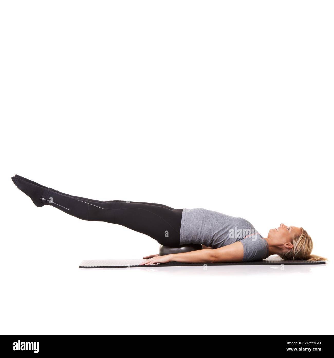 Tensing her muscles for balance. A young woman lying on an exercise ...