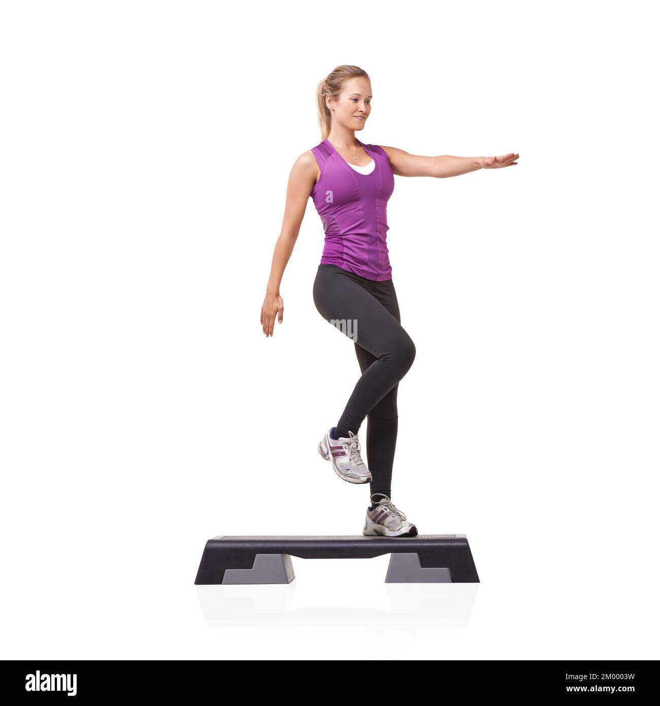 Stepping up her fitness levels. A smiling young woman doing aerobics on ...