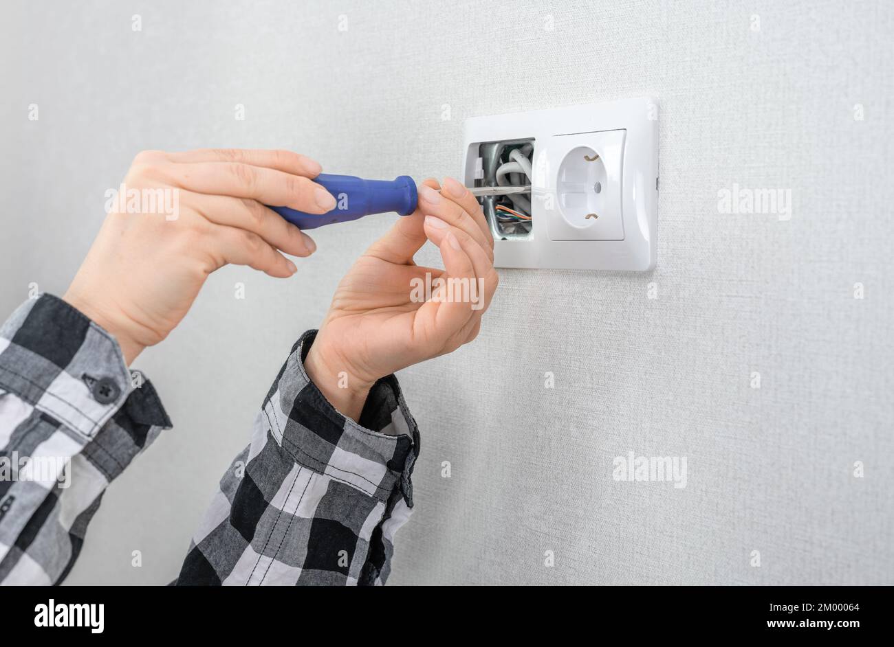Electrician is using screwdriver to install power outlet in to plastic ...