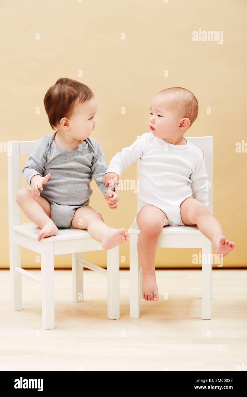 Making new friends. Adorable shot of two cute babies sitting on chairs ...