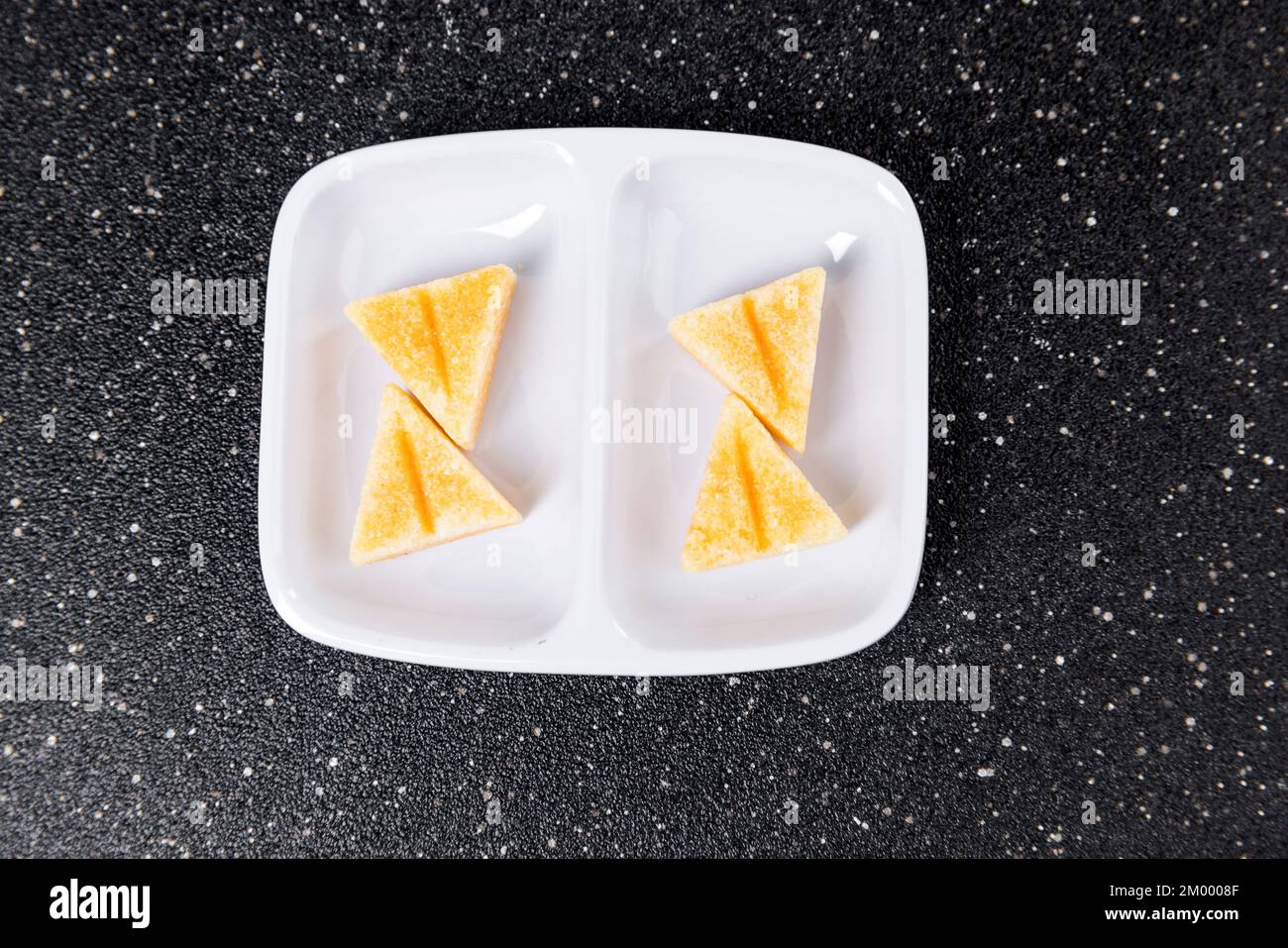 Saffron spiced sugar four cubes in a divided tray over black Stock ...