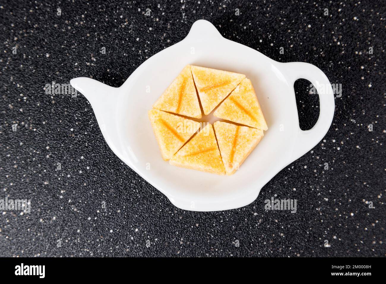 Saffron spiced sugar six cubes in a tea pot shaped tray over black ...