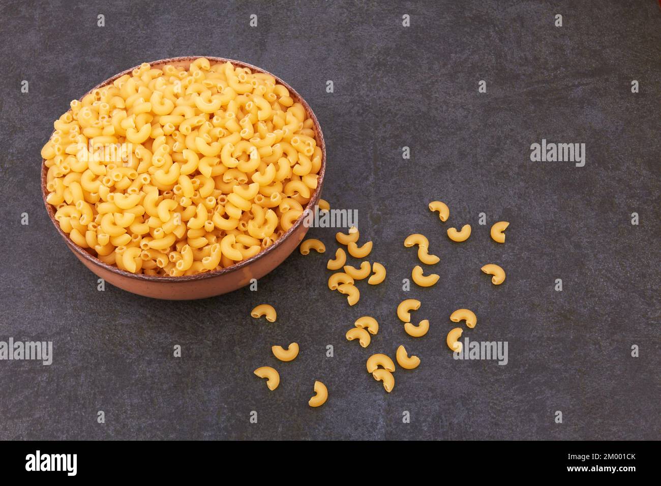 Elbow macaroni on a stone black background Stock Photo - Alamy