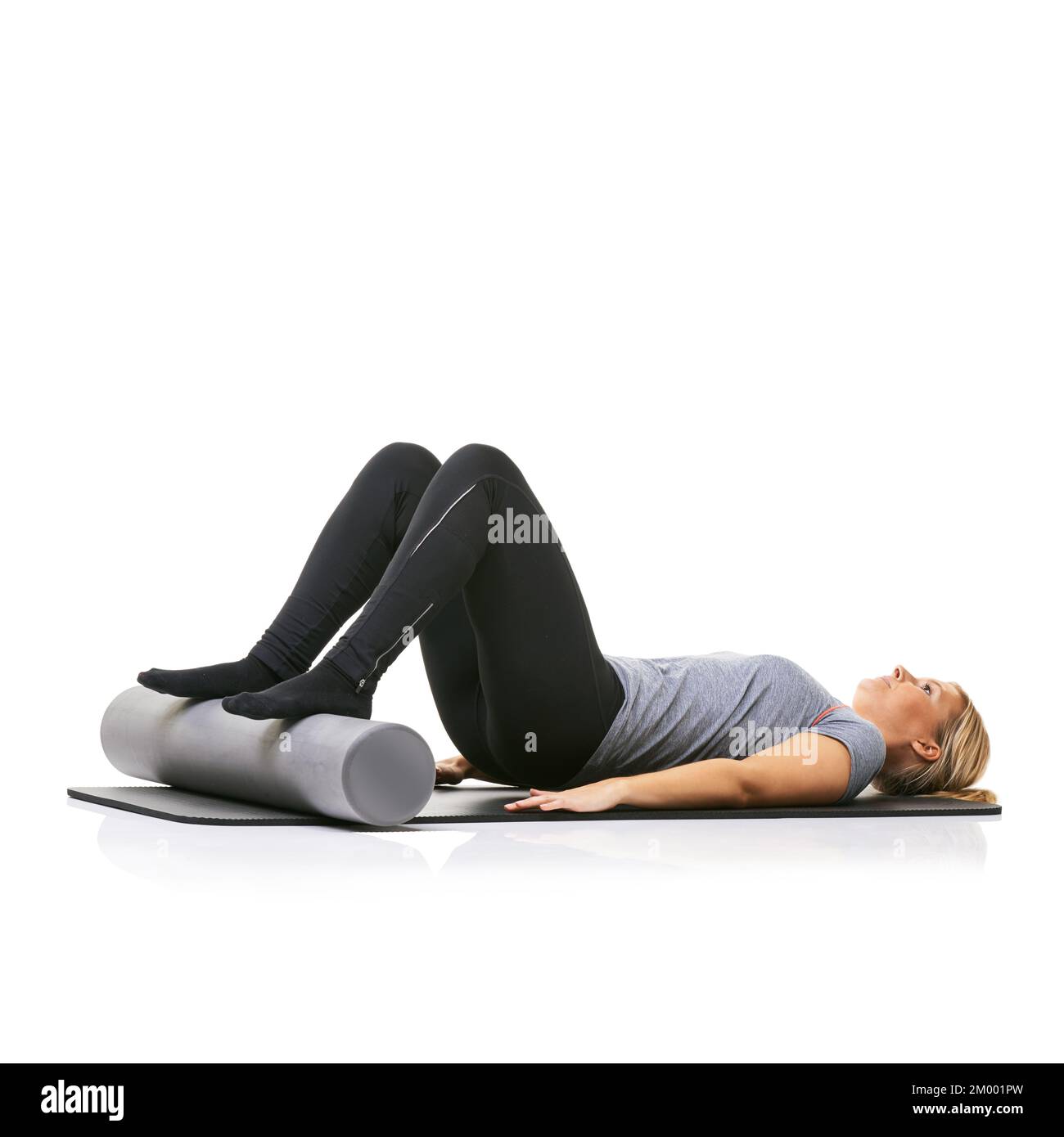 Using a foam-roller to raise her legs. A young woman lying on an ...