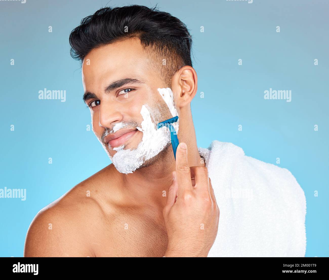 Man, face and shaving in studio for skincare, wellness and towel in portrait by blue background ...