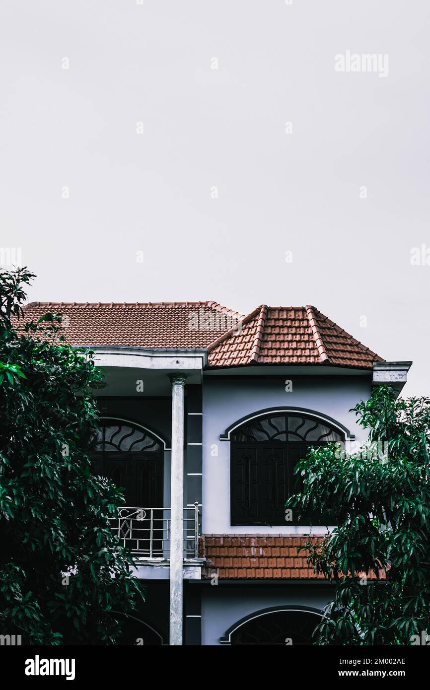 Vertical photo modern roof red tiles two-story building top floor trees ...