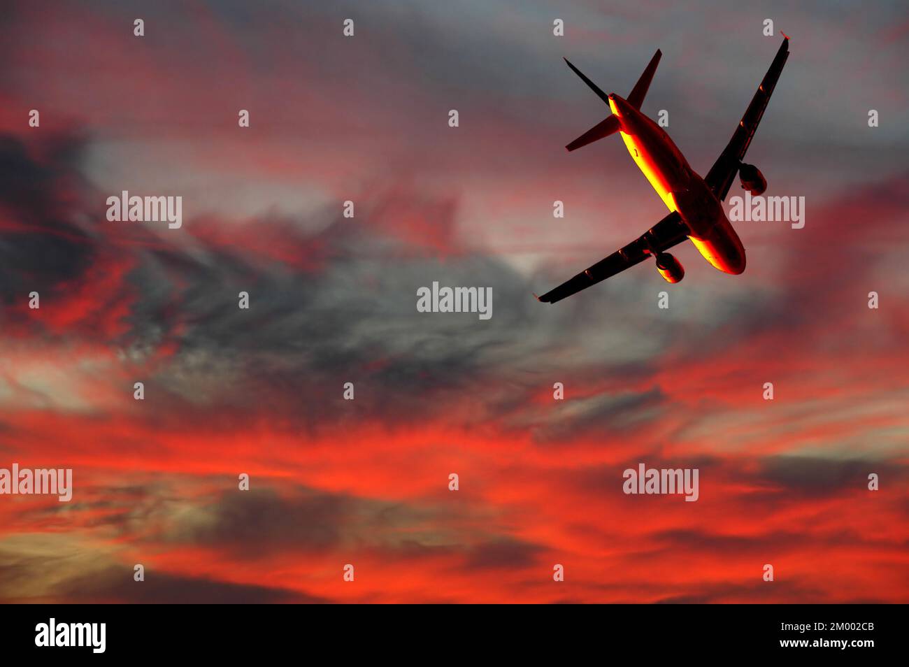 Plane is flying while the sun is setting Stock Photo - Alamy