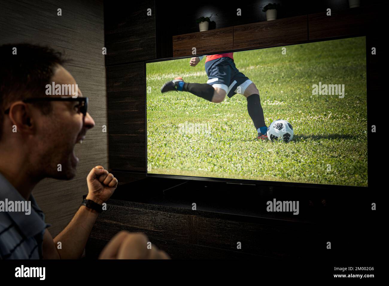 a man screams emotionally while watching TV. A fan is rooting for his ...