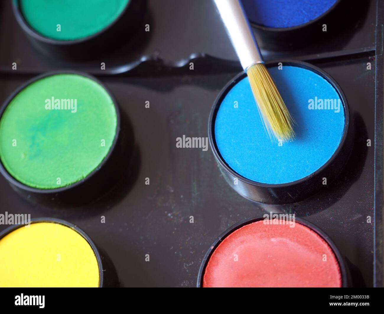 Paint brush standing on blue in paint palette Stock Photo - Alamy