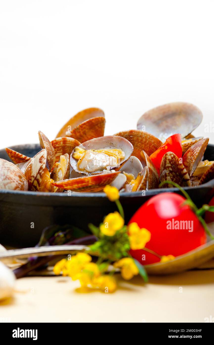 Fresh clams stewed on an iron skillet over wite rustic wood table Stock ...