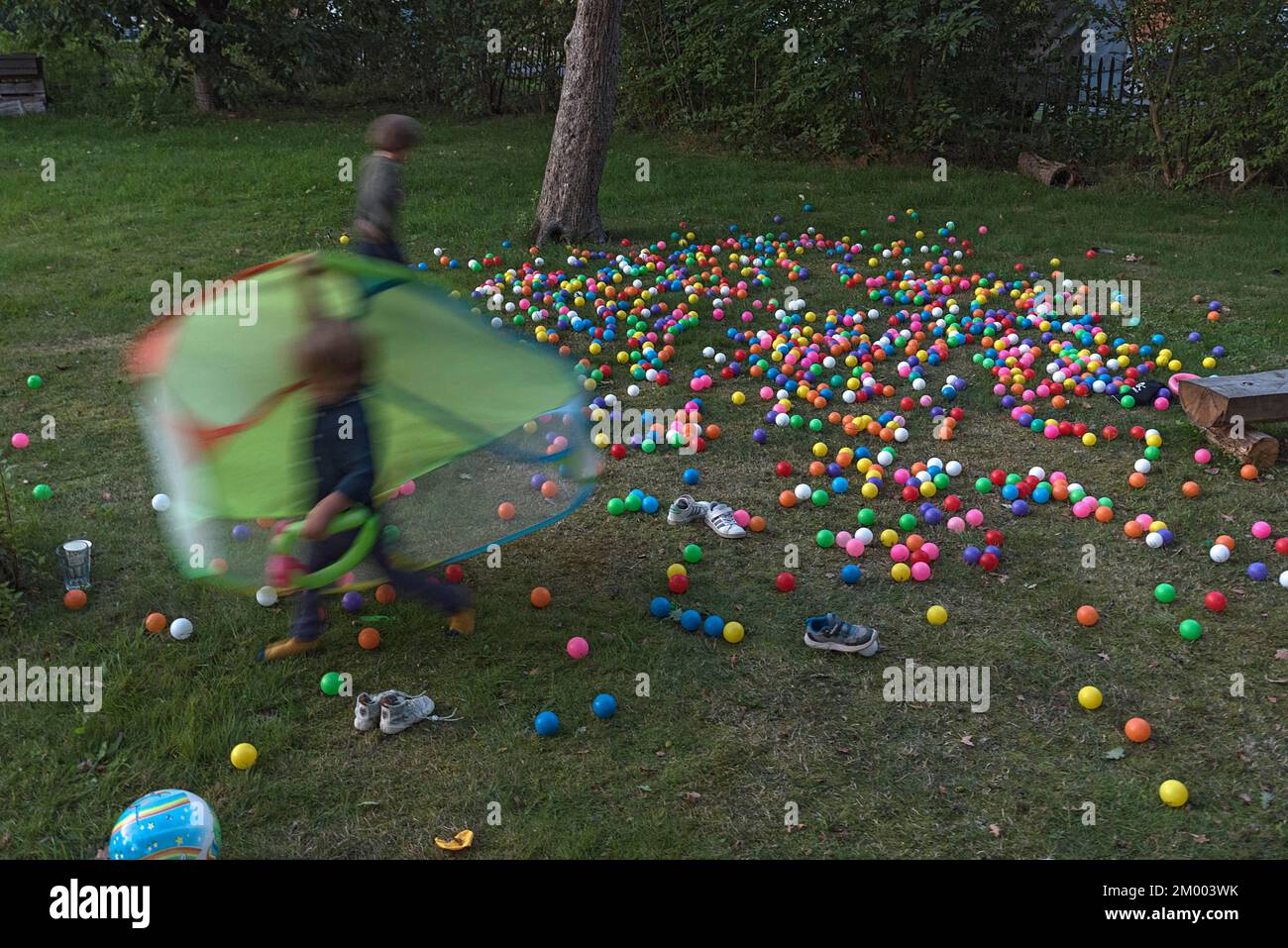 Children playing with coloured balls in a garden, Lower Saxony, Germany ...