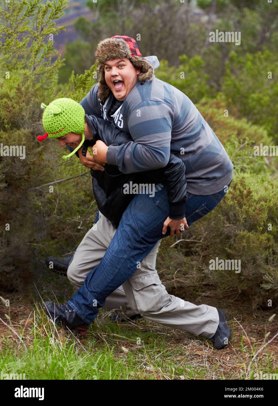 Giving my buddy a lift. An overweight young man being piggy-backed by ...