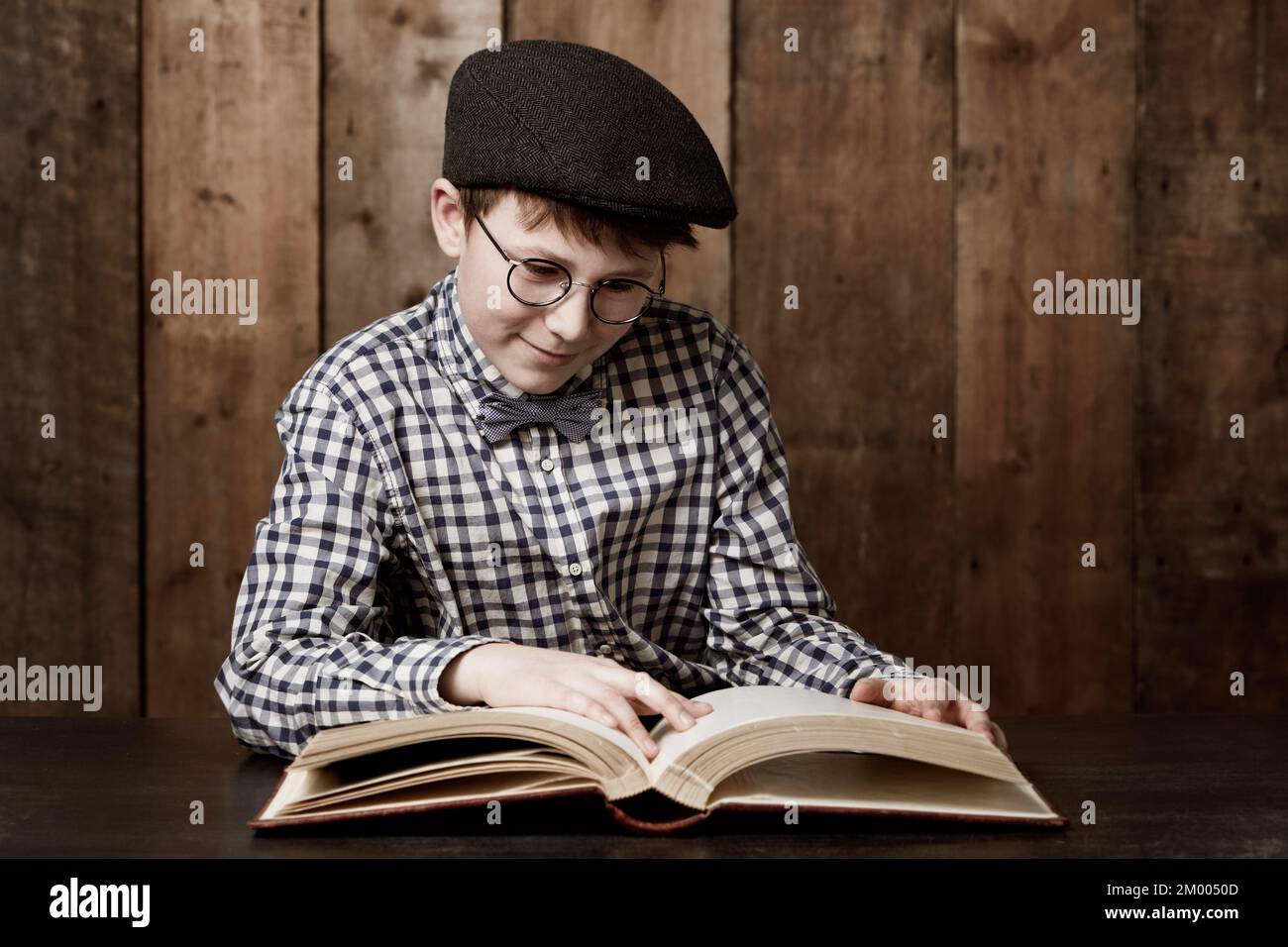Reading his way to greater knowledge. Young boy in retro clothing ...