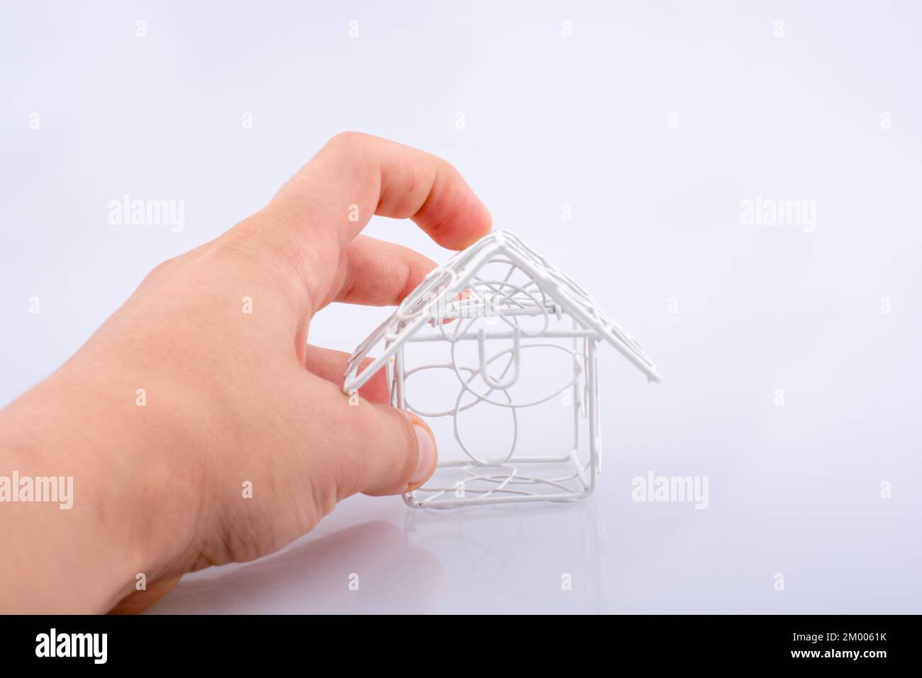 Little metal house and a hand on awhite background Stock Photo - Alamy