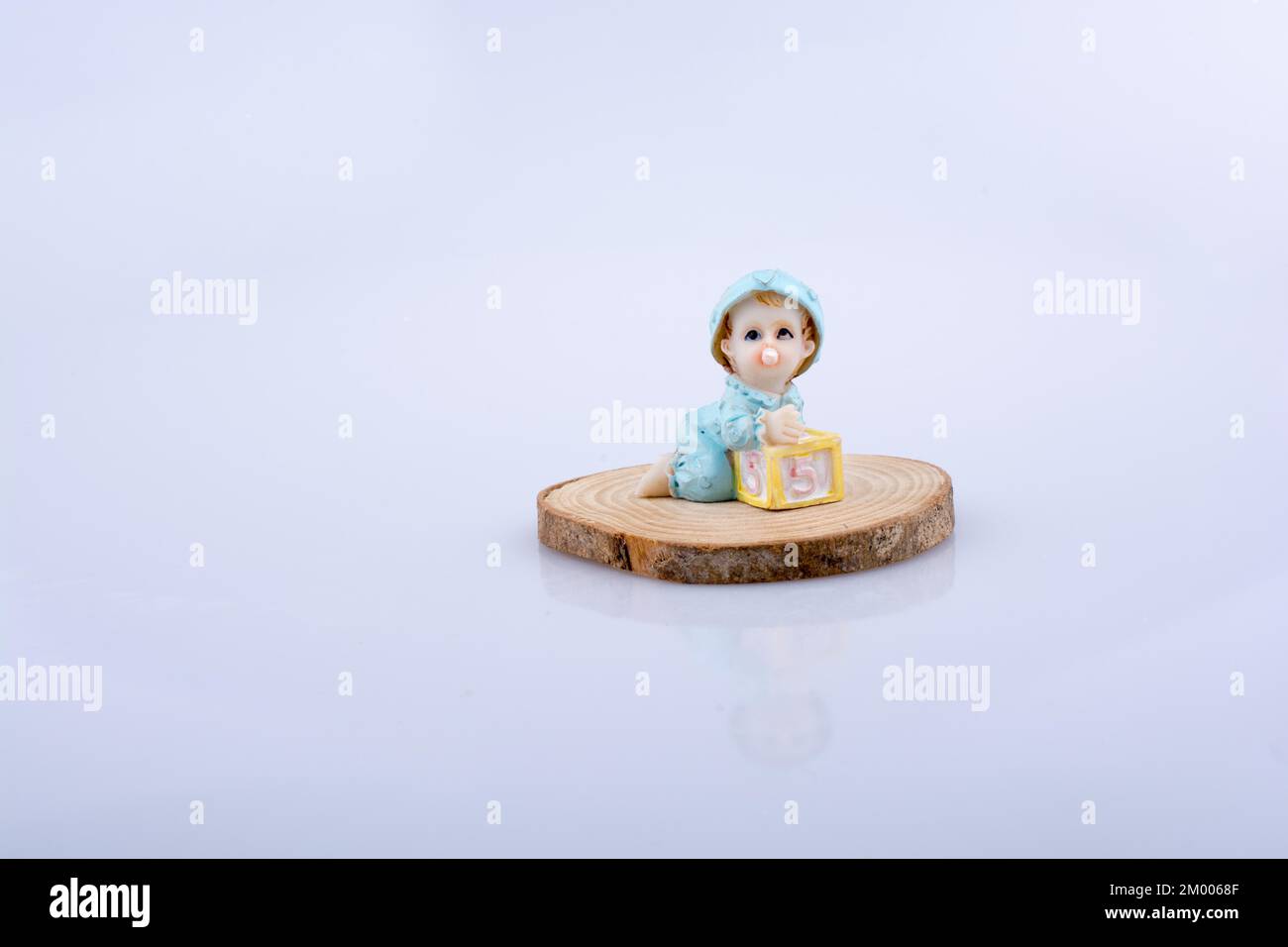 Little baby figure on a piece of wood on a white background Stock Photo ...