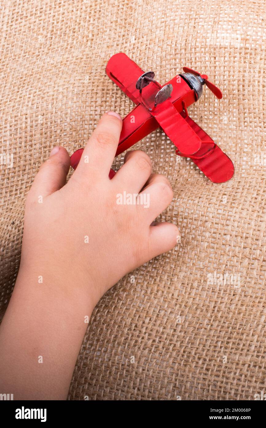 Hand holding a red toy plane on a linen canvas Stock Photo - Alamy