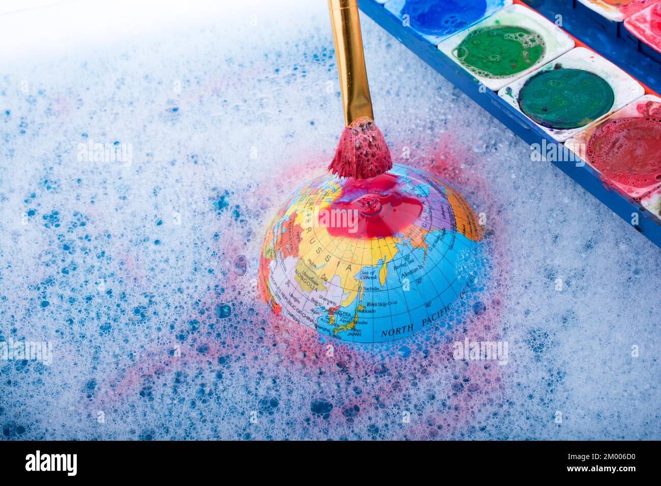 Paint dissolving through painting brush on the top of globe Stock Photo ...