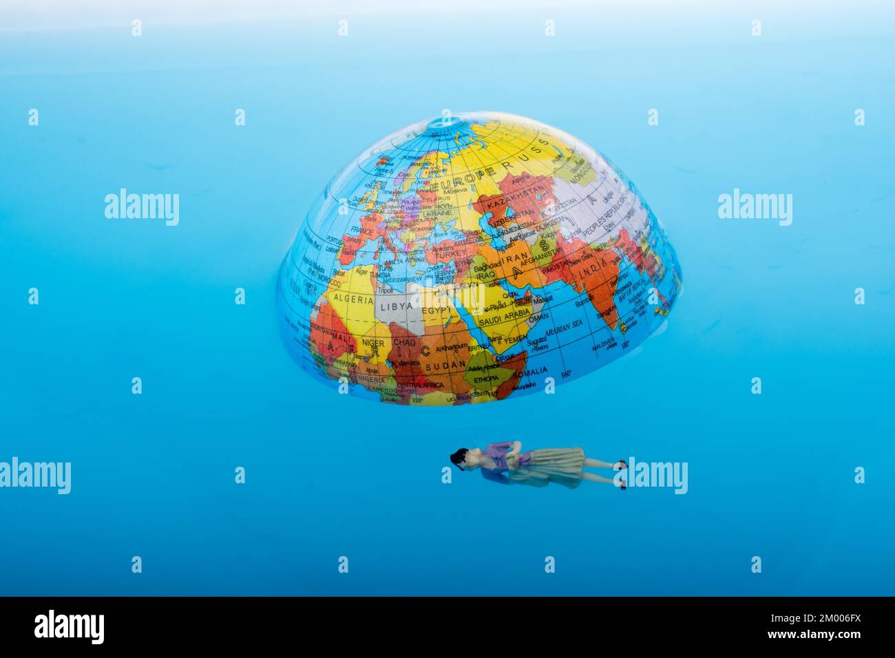 Little globe with floating figurine around in water Stock Photo - Alamy