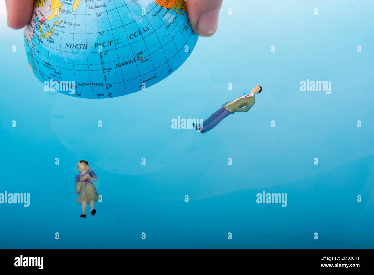 Little globe with floating figurines around in water Stock Photo - Alamy