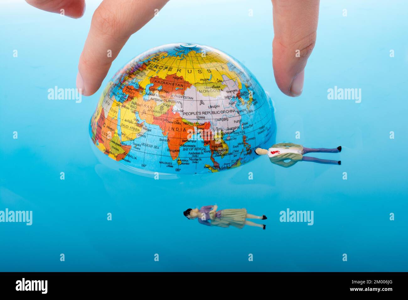 Little globe with floating figurines around in water Stock Photo - Alamy